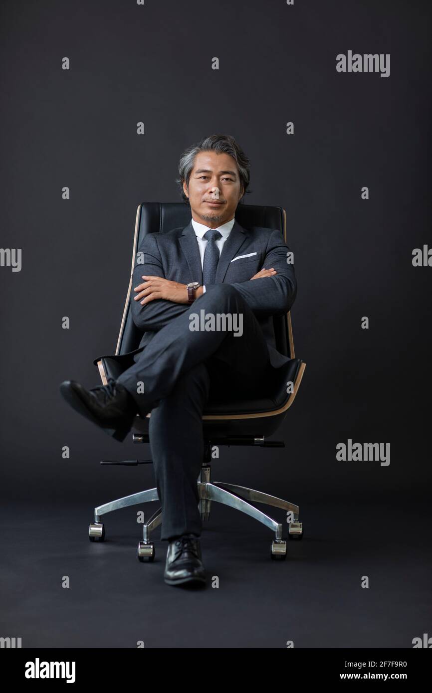 Confident businessman sitting on chair Stock Photo - Alamy