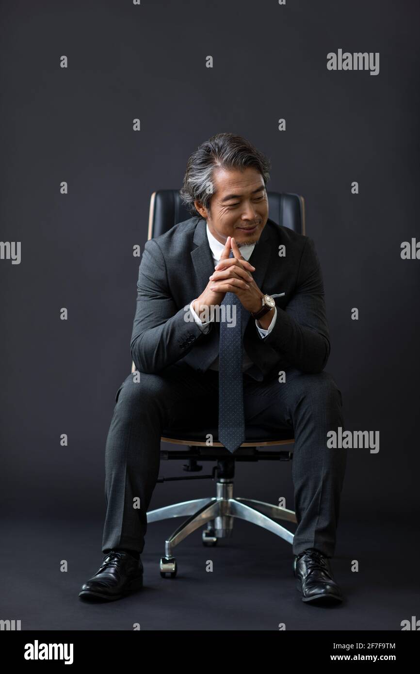 Confident businessman sitting on chair Stock Photo - Alamy