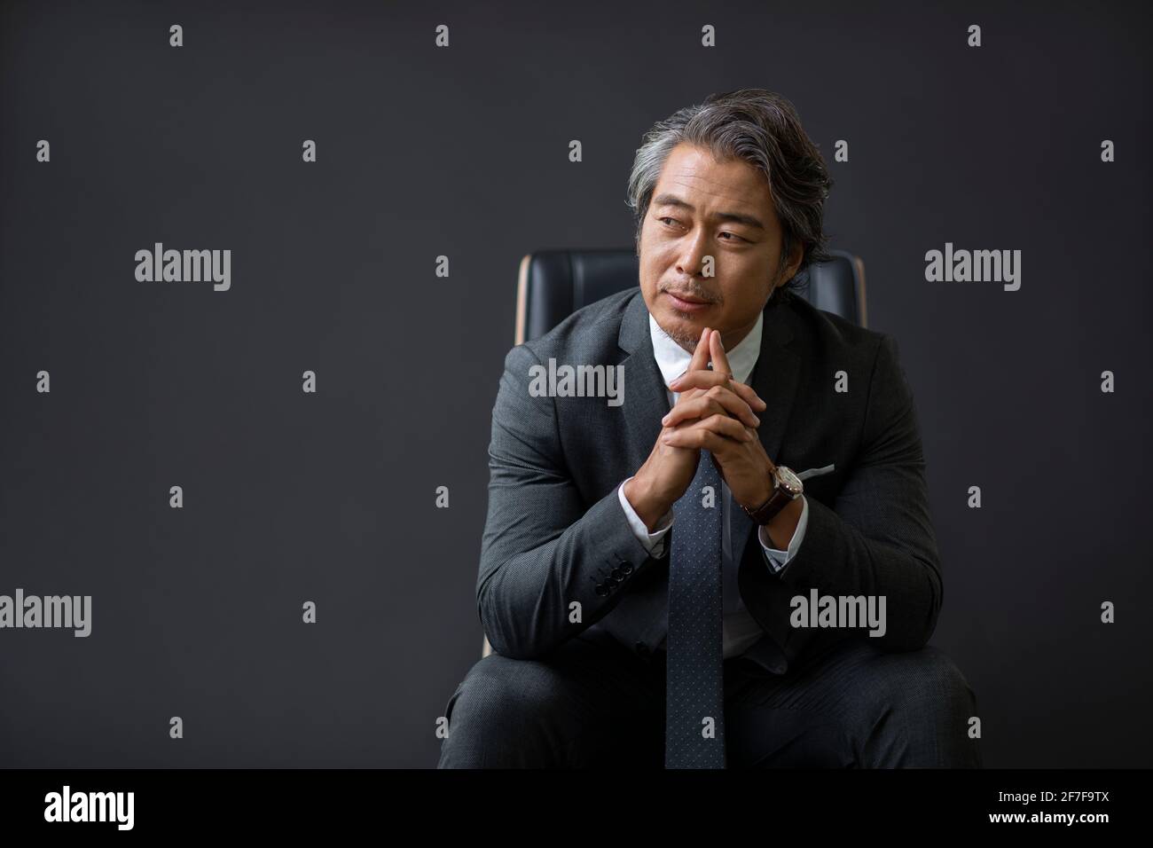 Confident businessman sitting on chair Stock Photo - Alamy