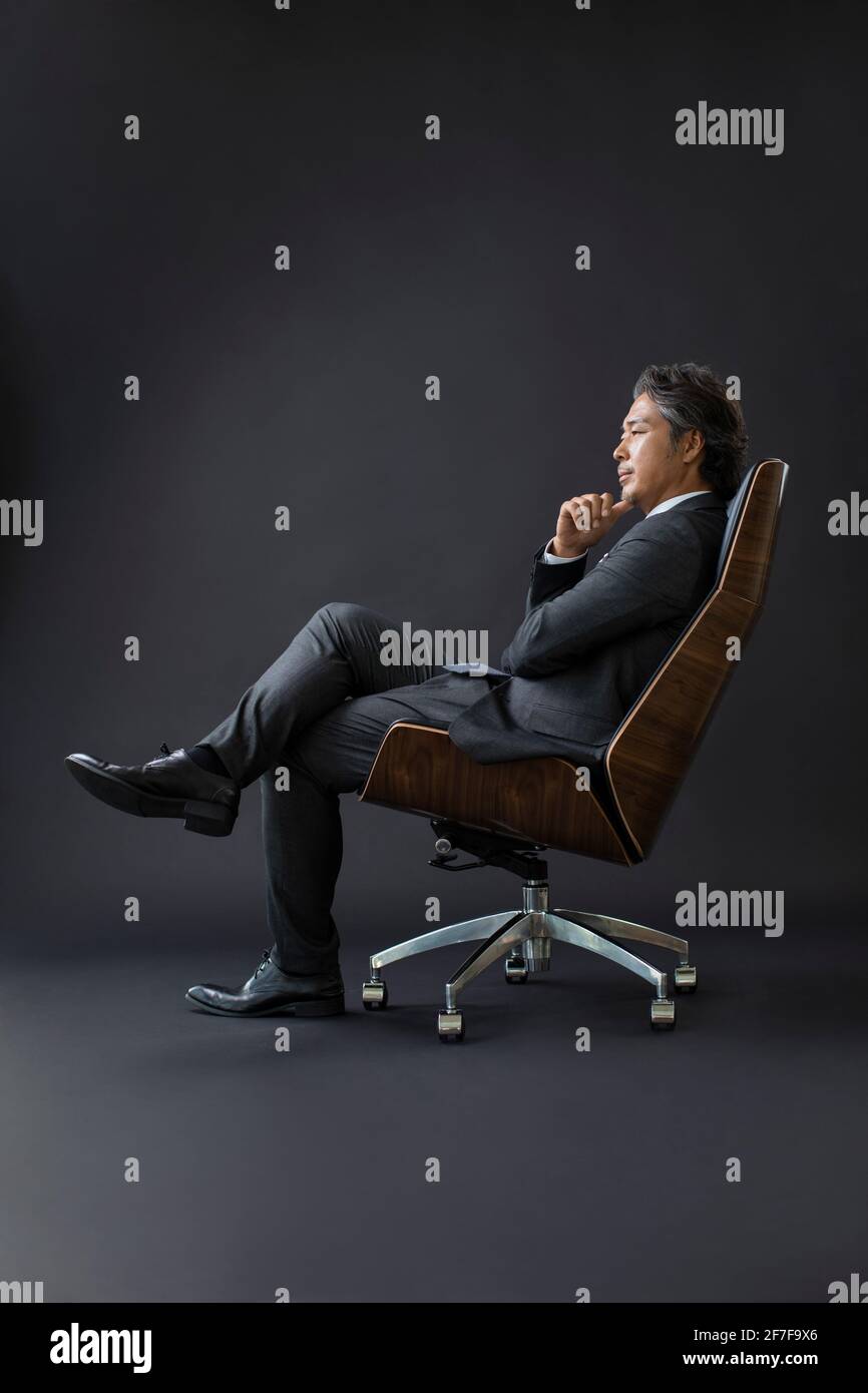 Confident businessman sitting on chair Stock Photo - Alamy