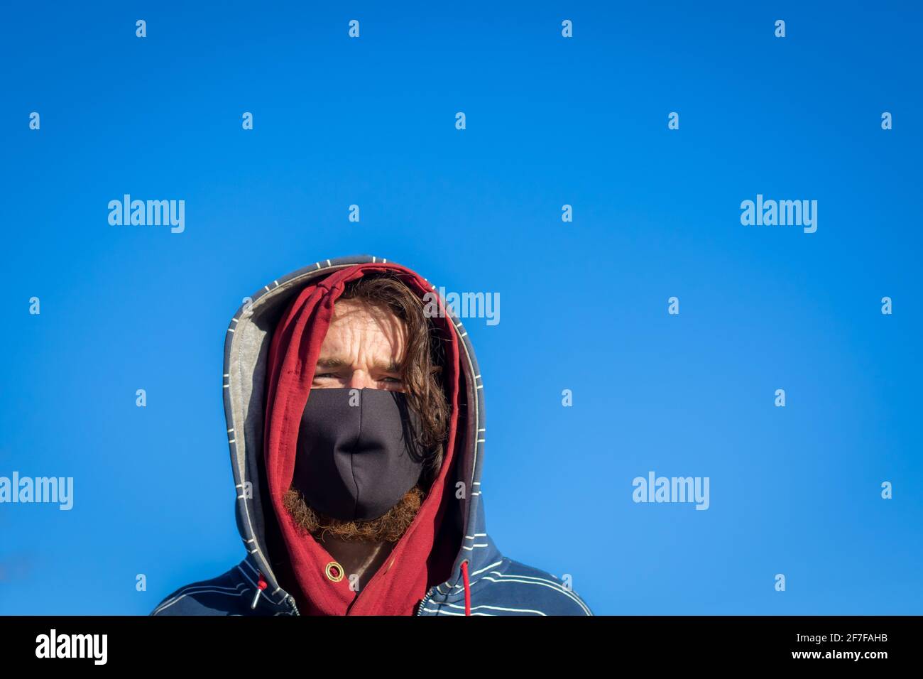 Ginger bearded Irish man with a face mask and hoods in front of a blue ...