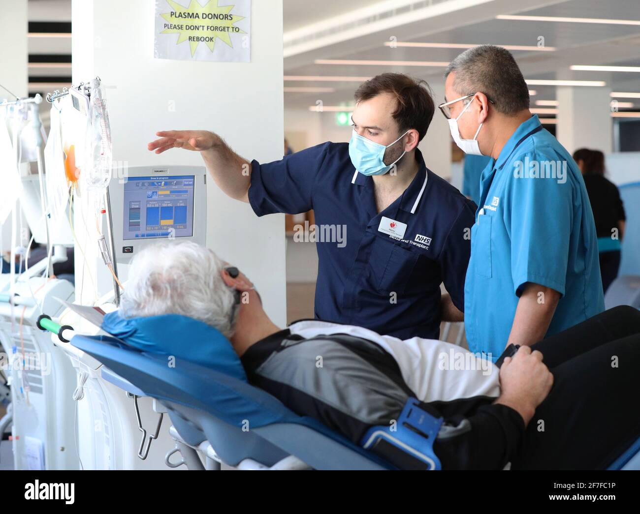 Donor carers manipulate the screen of an apheresis machine which ...