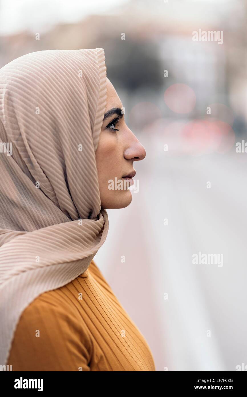 Beautiful young muslim woman standing in the street and looking at ...