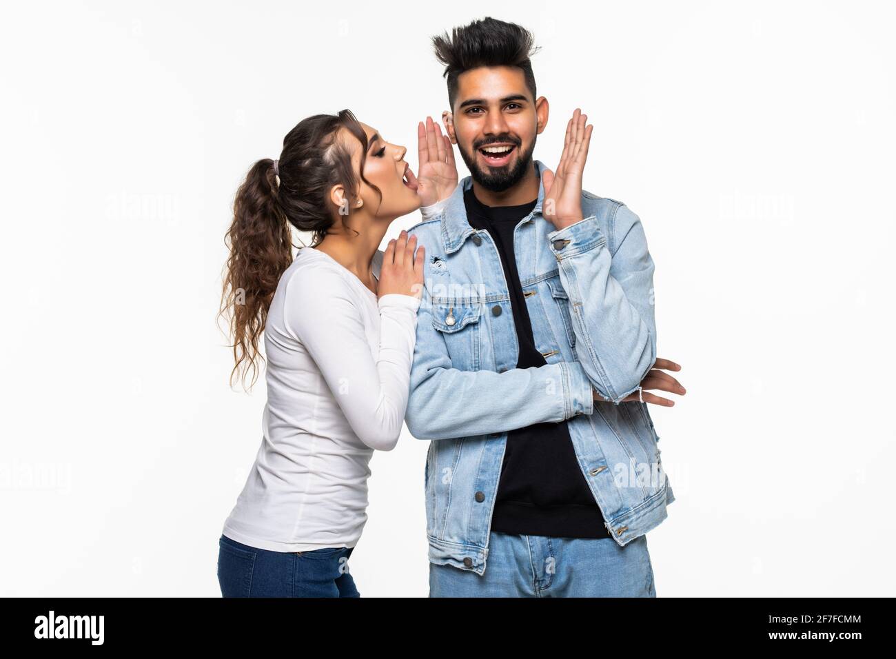 Portrait of a young indian couple telling secrets standing together ...