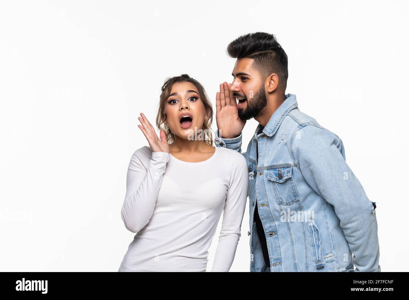 Portrait of a young indian couple telling secrets standing together ...