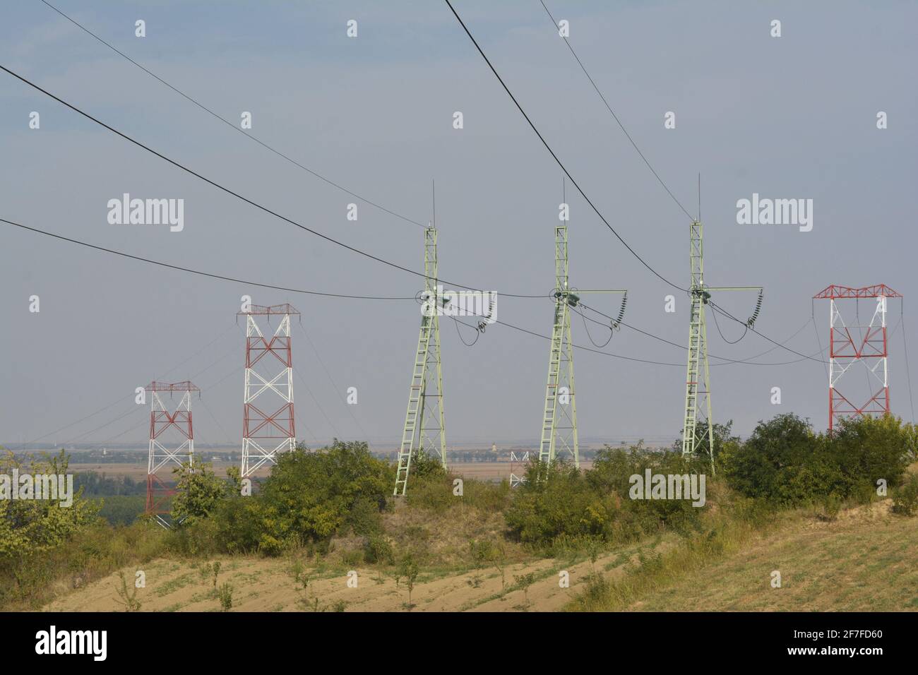 transmission lines in rural area with a grass, trees and sky in ...