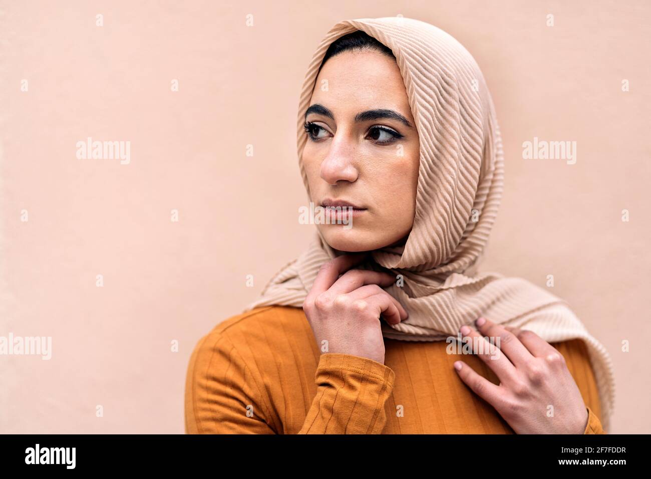 Beautiful young muslim woman standing against pink background and ...