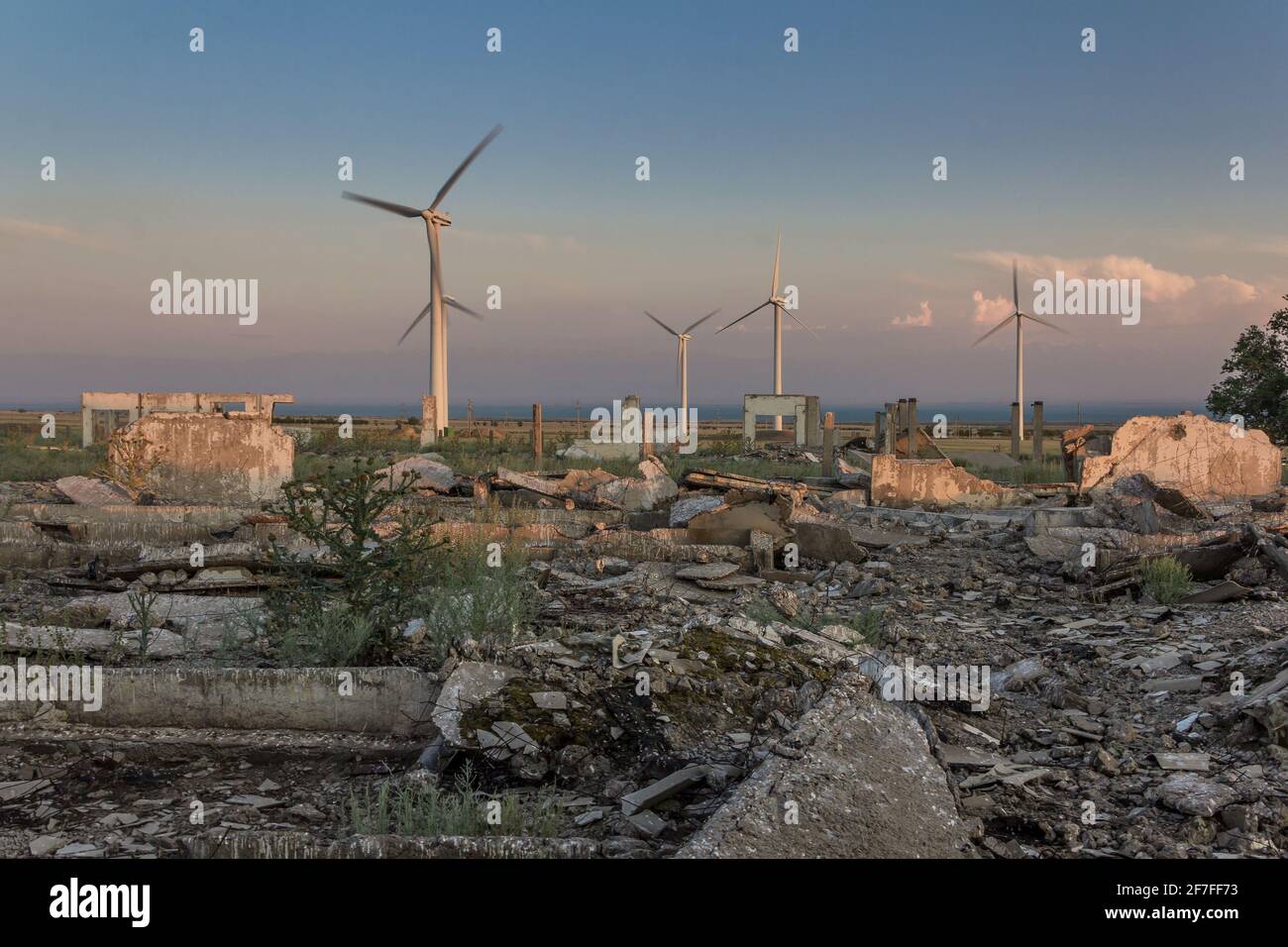 The ruins of a farm of Soviet times against the backdrop of modern wind ...