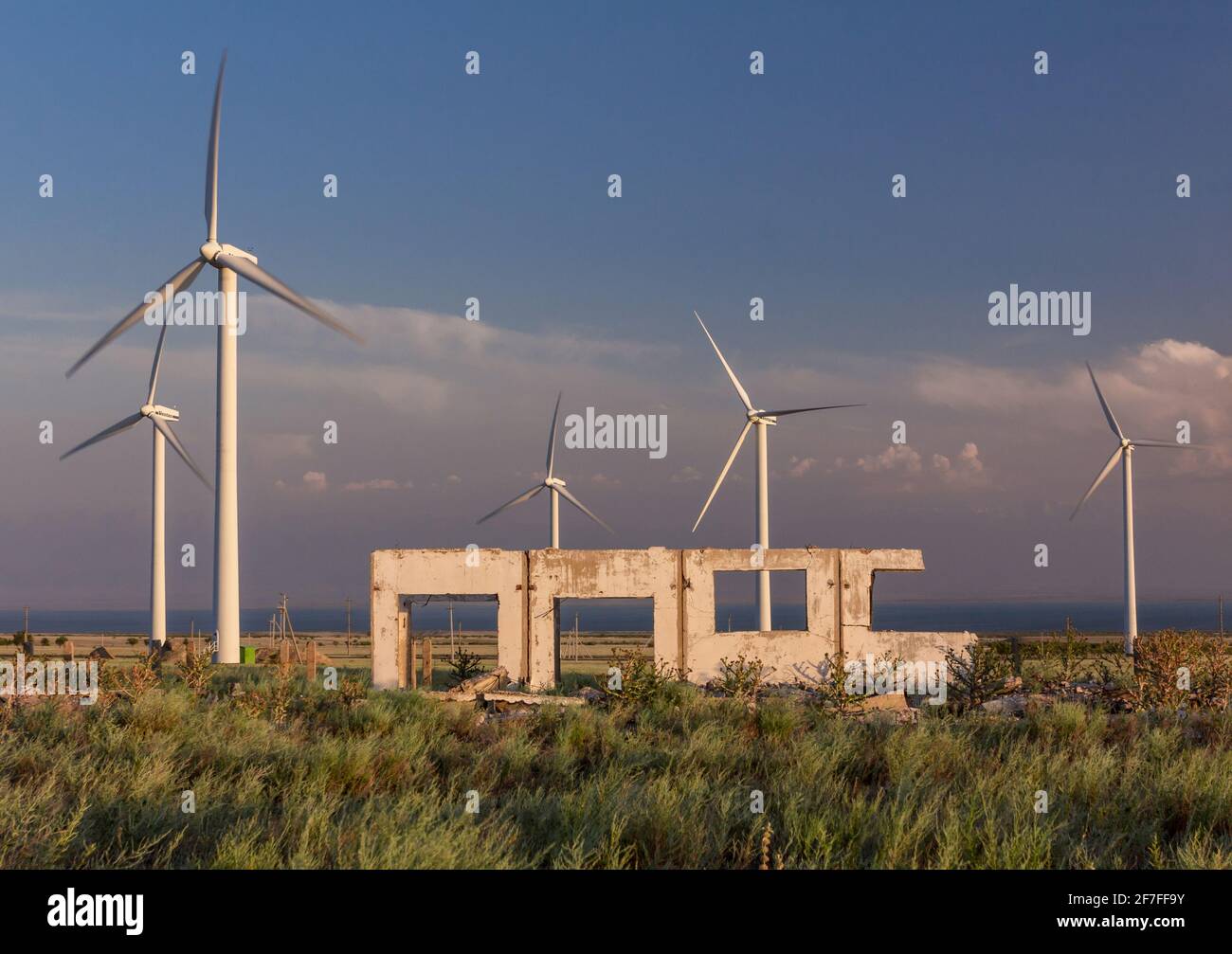The ruins of a farm of Soviet times against the backdrop of modern wind ...