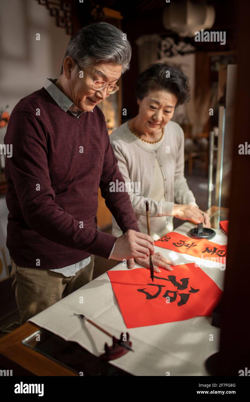 Happy senior couple writing calligraphy on couplets Stock Photo - Alamy