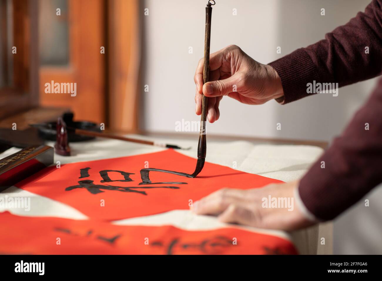 Senior man writing calligraphy on couplets Stock Photo - Alamy