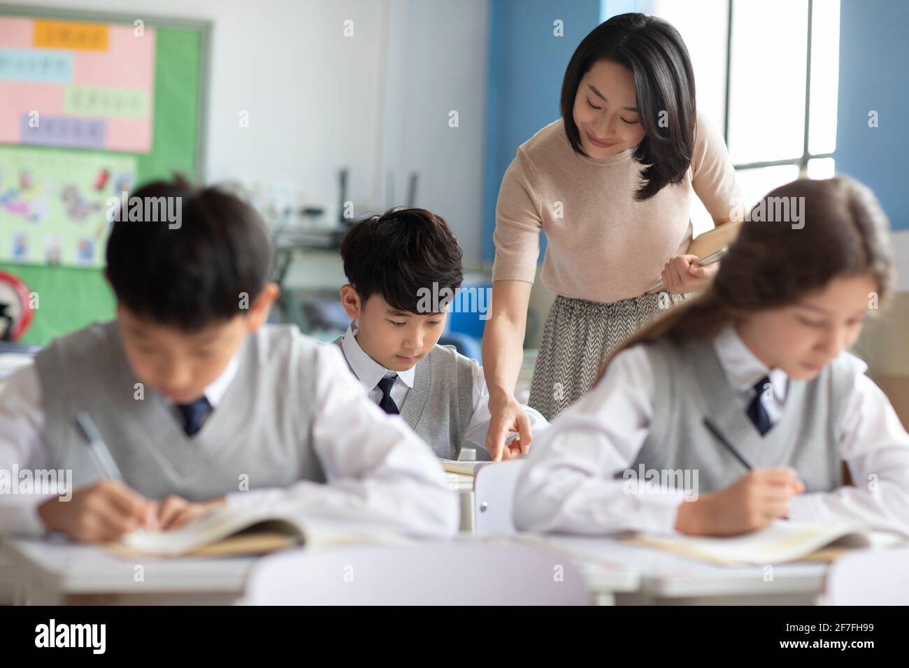 Young teacher helping students in classroom Stock Photo - Alamy