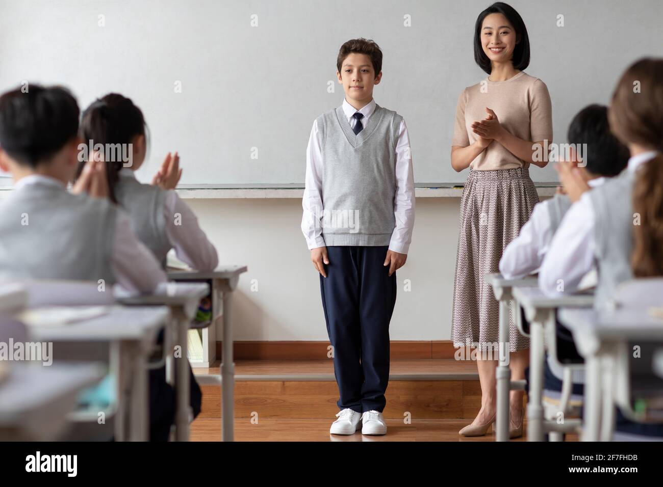 Young teacher introducing a new classmate in classroom Stock Photo - Alamy