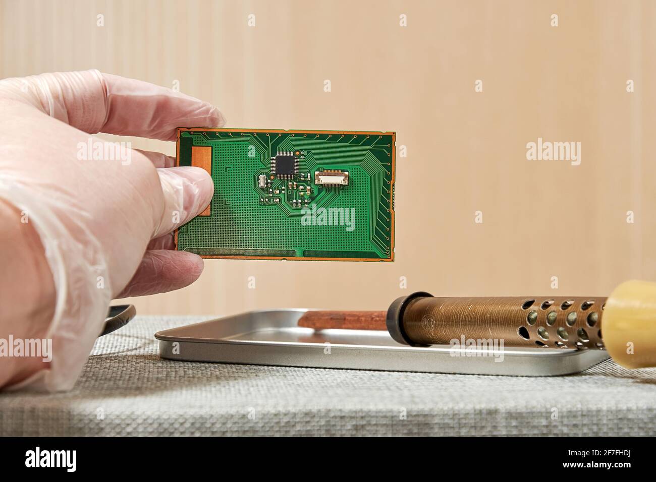 Man's hand keeps a PCB with a chip in the laboratory above the table ...