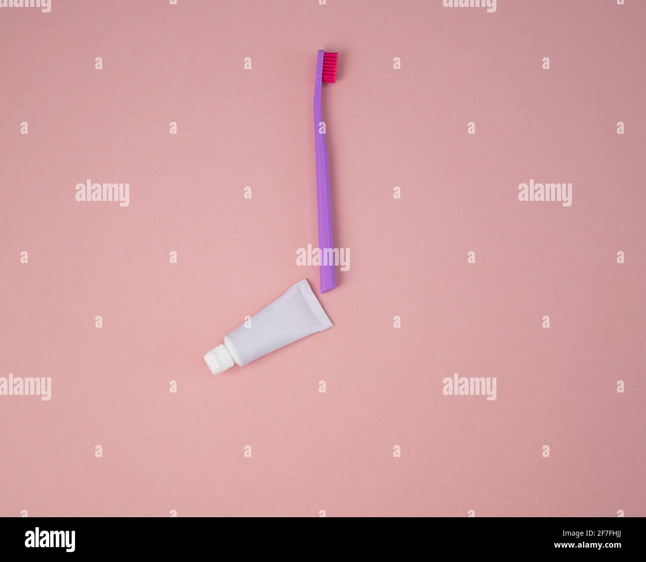 Toothbrush and a tube of toothpaste on a pink background. Oral hygiene ...