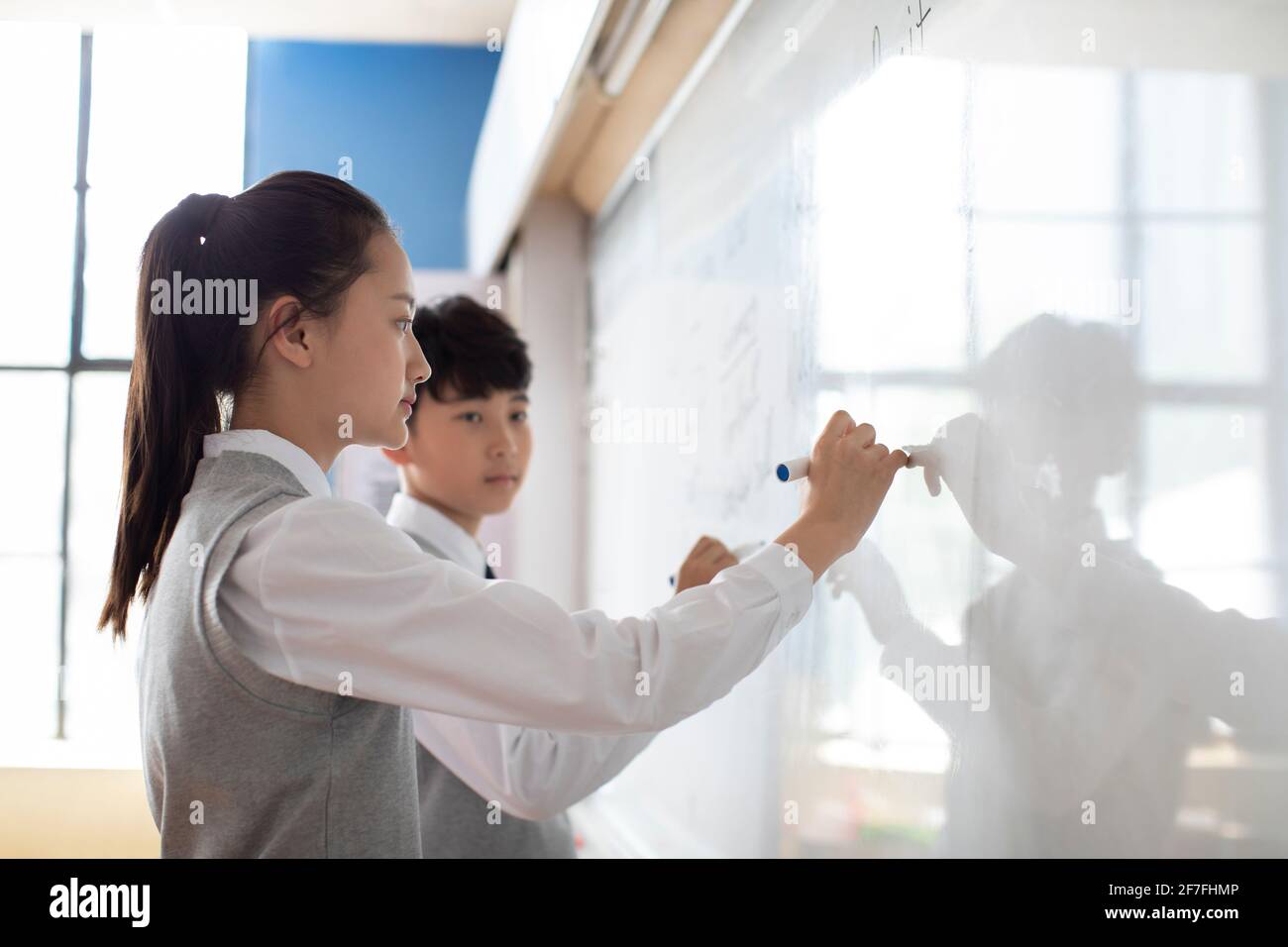 Students writing on whiteboard Stock Photo - Alamy