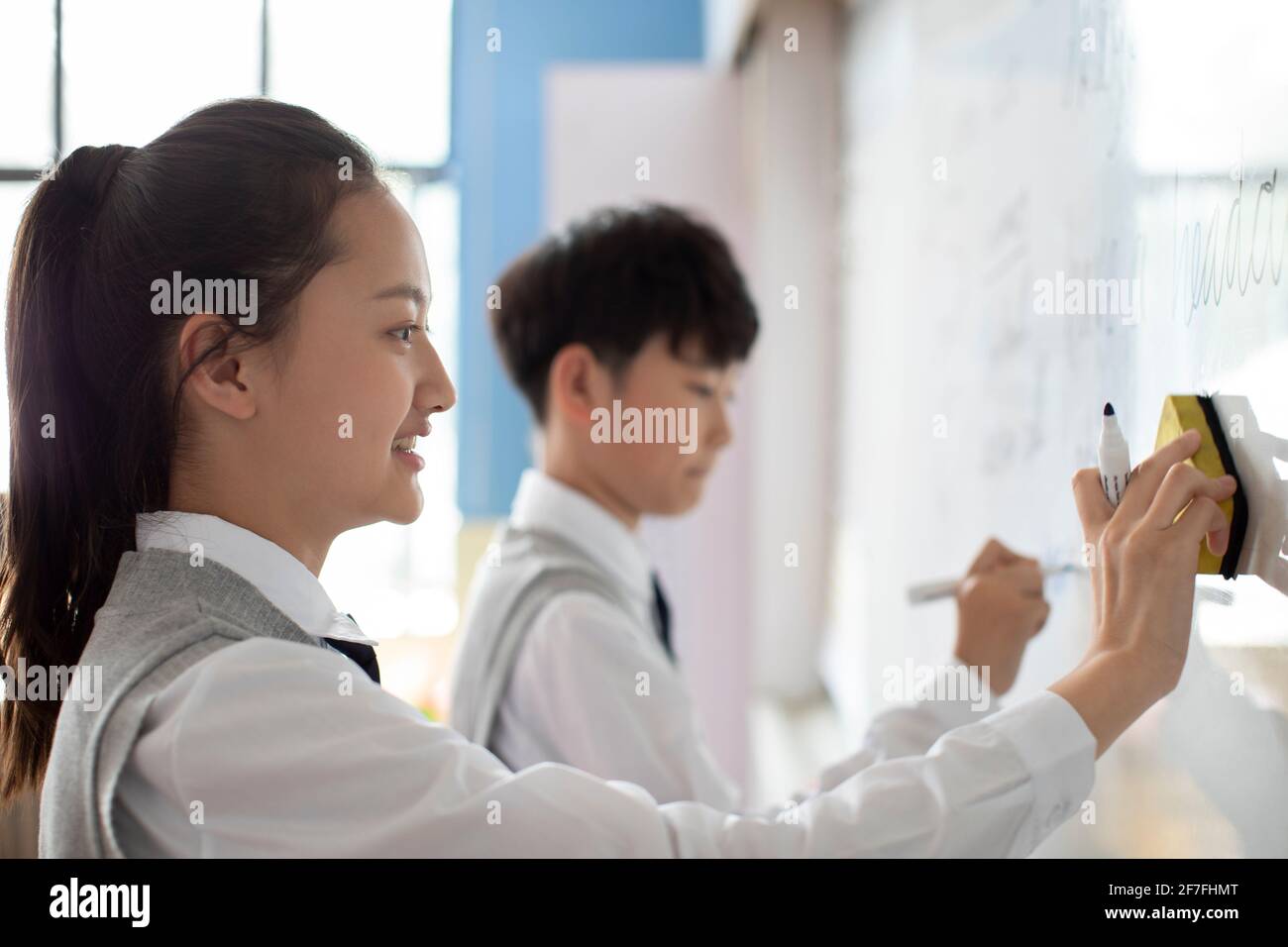Students writing on whiteboard Stock Photo - Alamy
