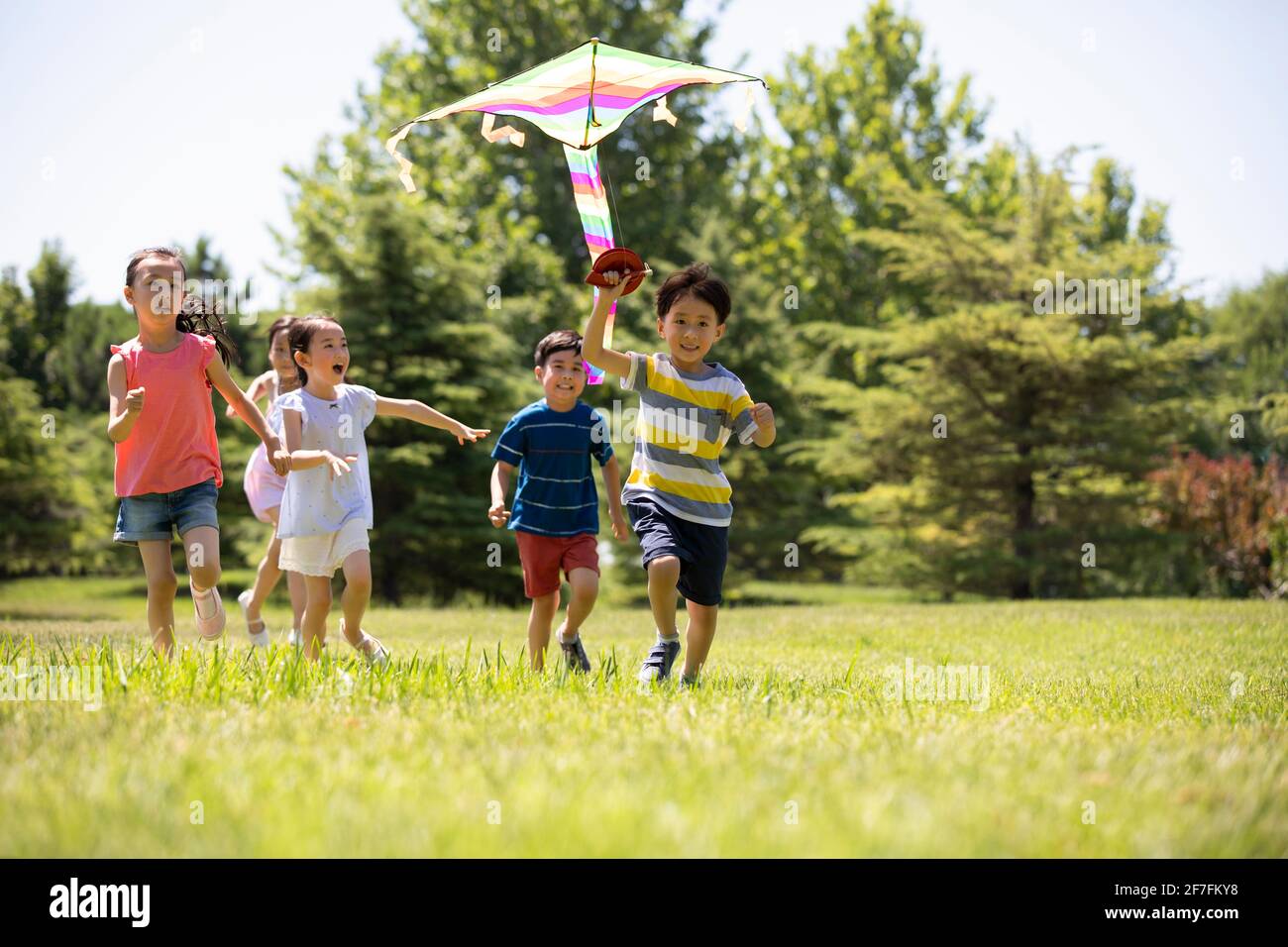 Happy children running with a kite on meadow Stock Photo - Alamy