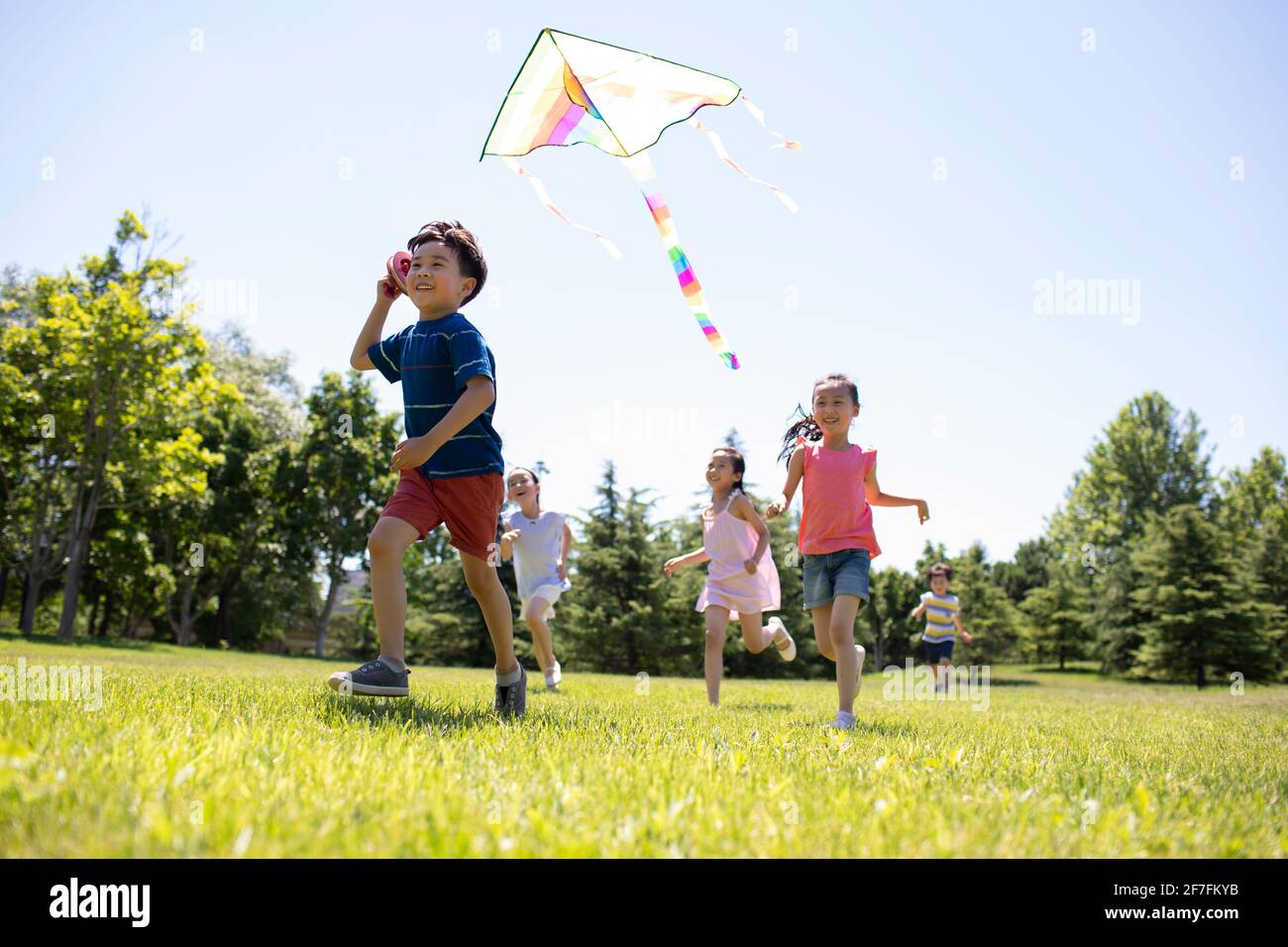 Happy children running with a kite on meadow Stock Photo - Alamy
