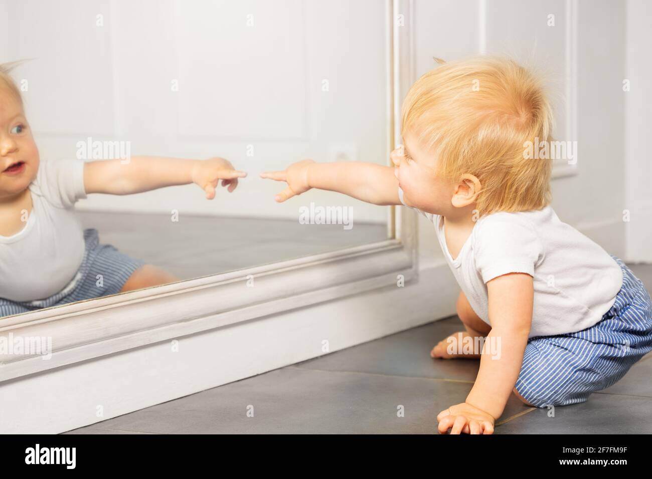 Blond toddler boy point to the mirror with finger Stock Photo - Alamy