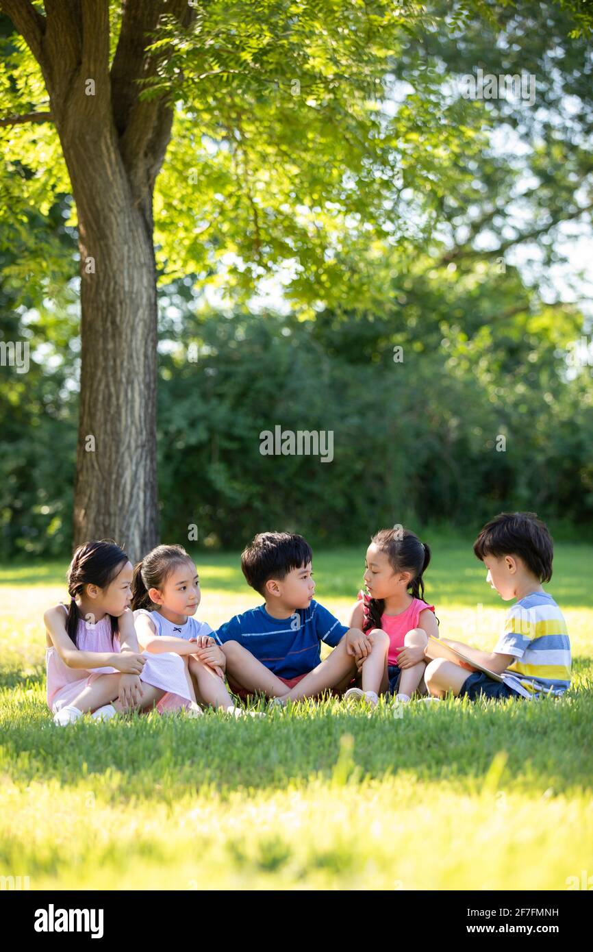 Happy children reading book on meadow Stock Photo - Alamy