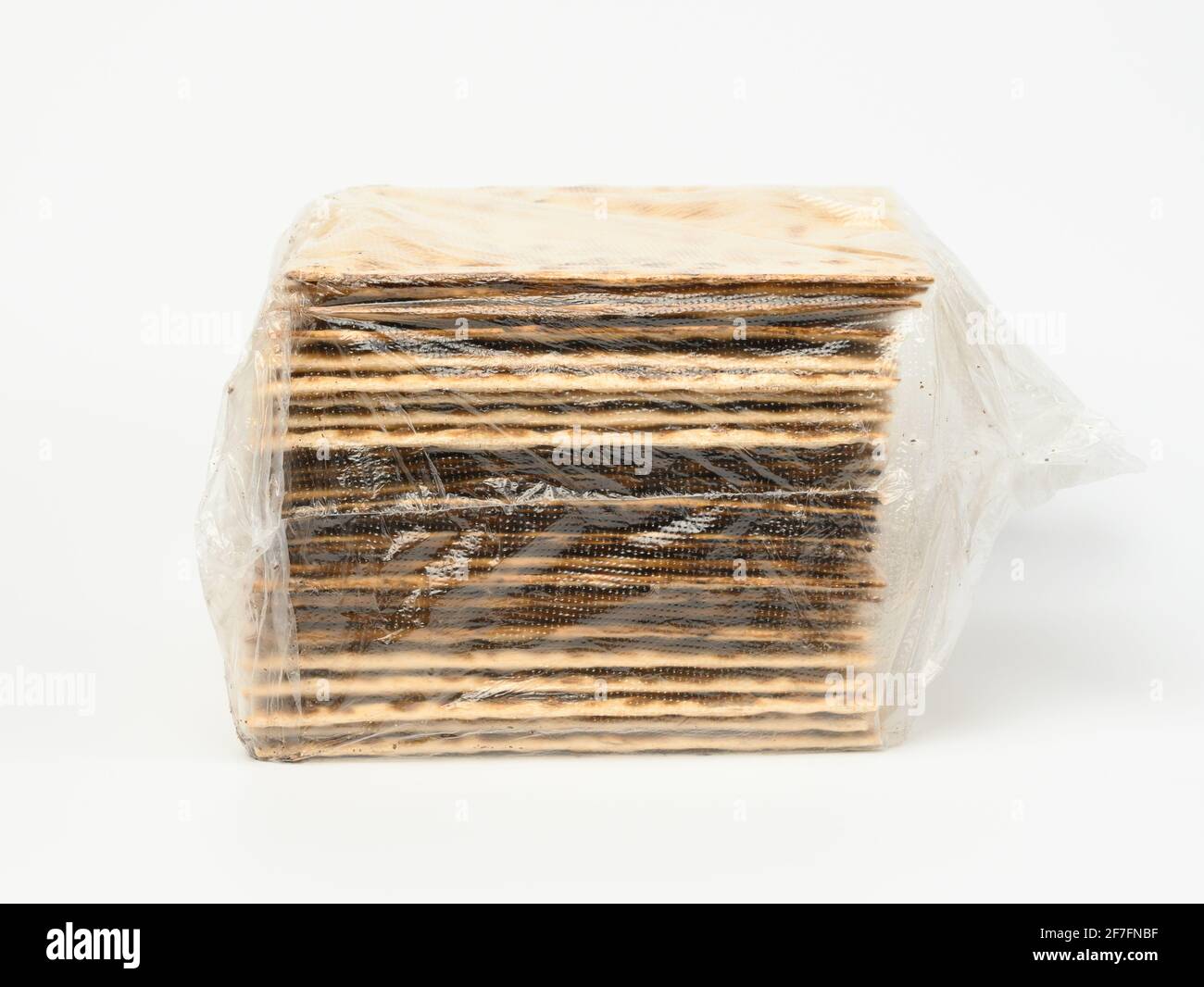 baked square matzo in a transparent bag on a white background, close up ...
