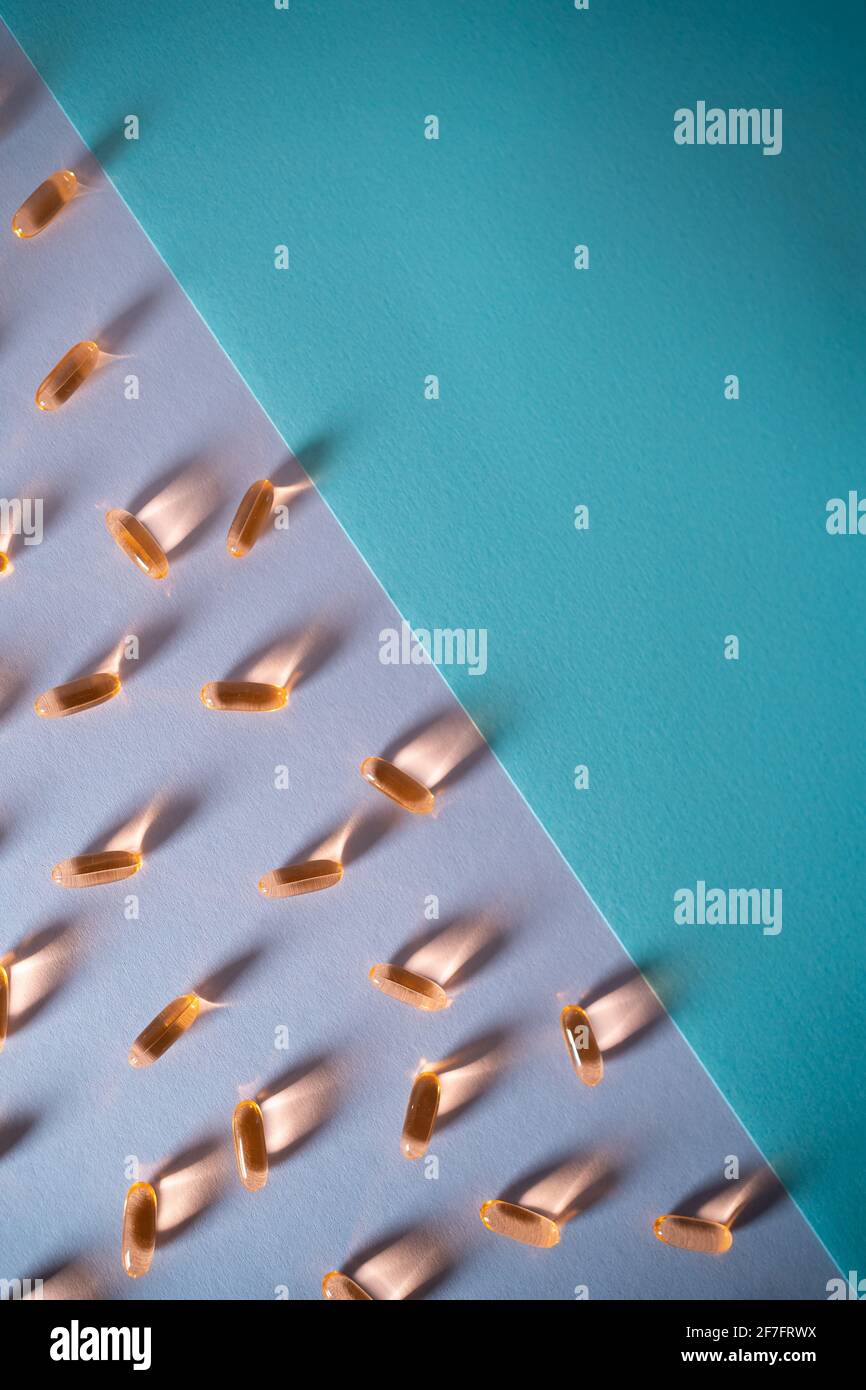 healthy golden fish oil capsules omega 3 vitamins on purple and blue ...