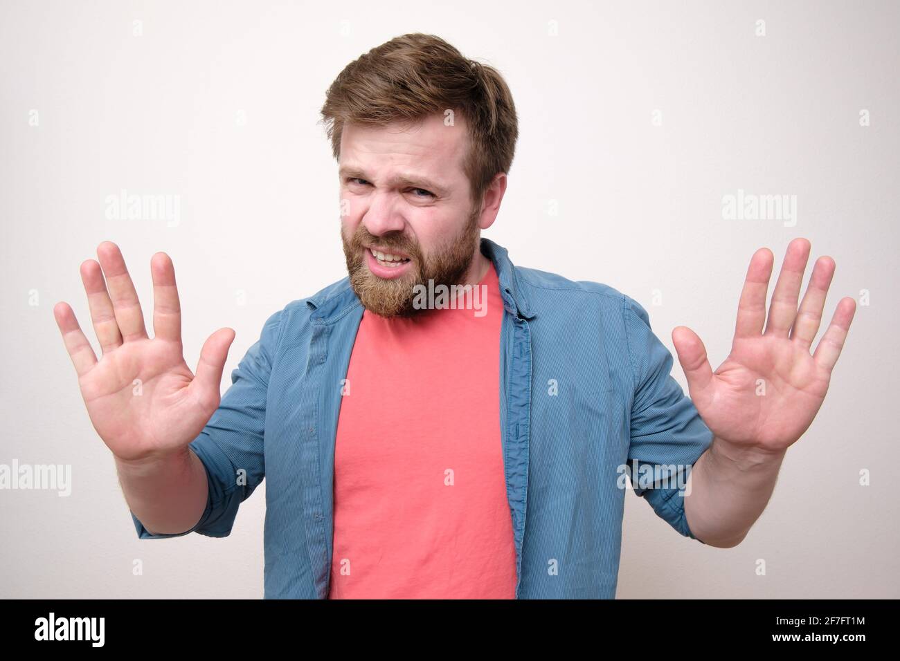Disgruntled bearded man makes a stop gesture with his palm, a gesture ...