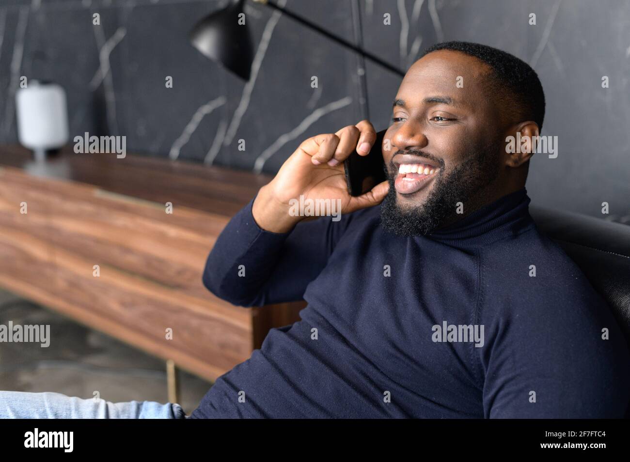 Hilarious African-American man talking the smartphone and laughs, a ...