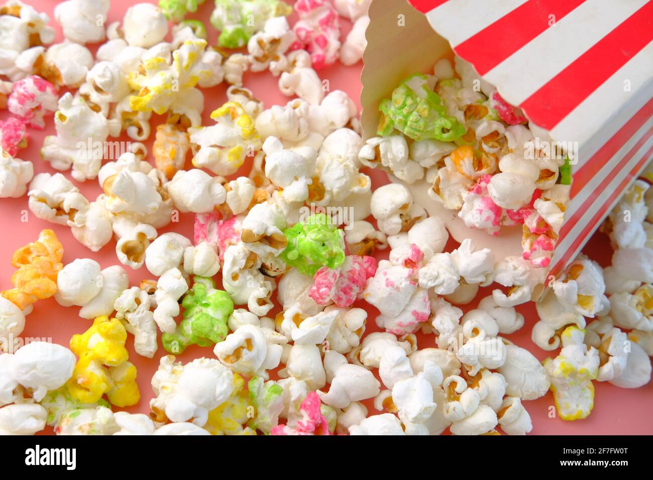 popcorn spilling from a container on red background Stock Photo - Alamy