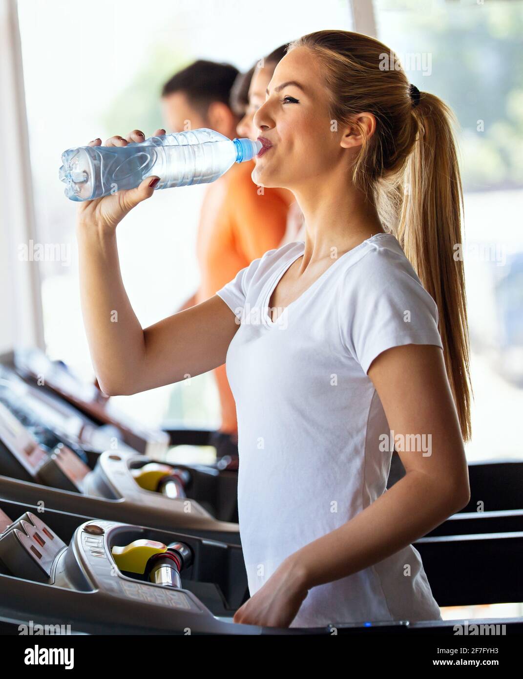Happy young fit woman drinking during workout, running in the gym Stock ...