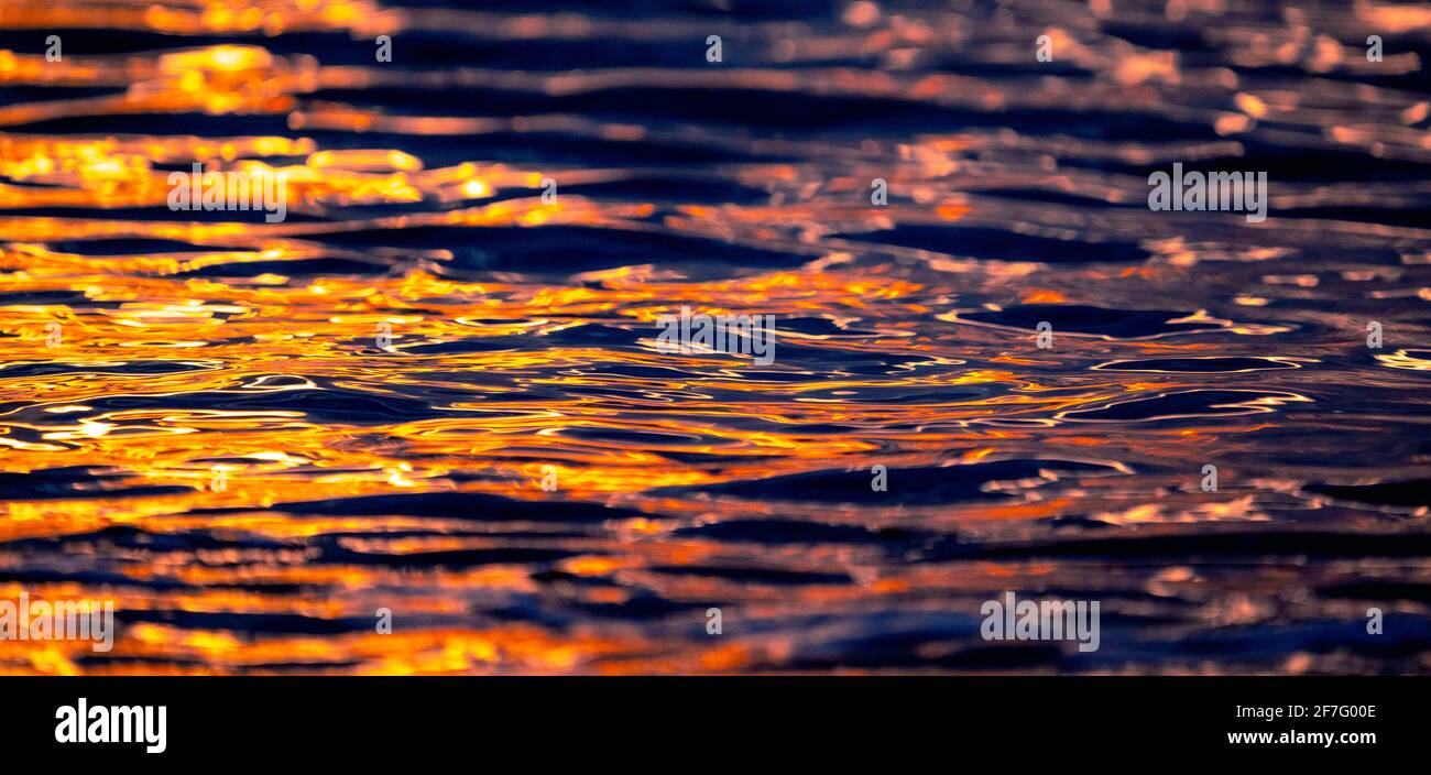 Sea waves texture with sunset or sunrise light reflecting on the water ...