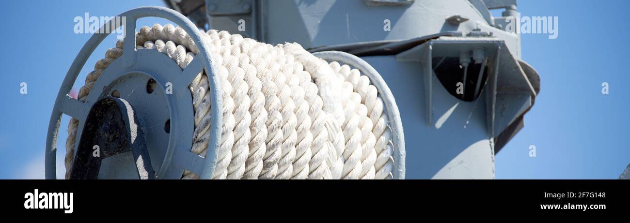 Cable reel with a white rope on the deck of the ship against blue sky ...