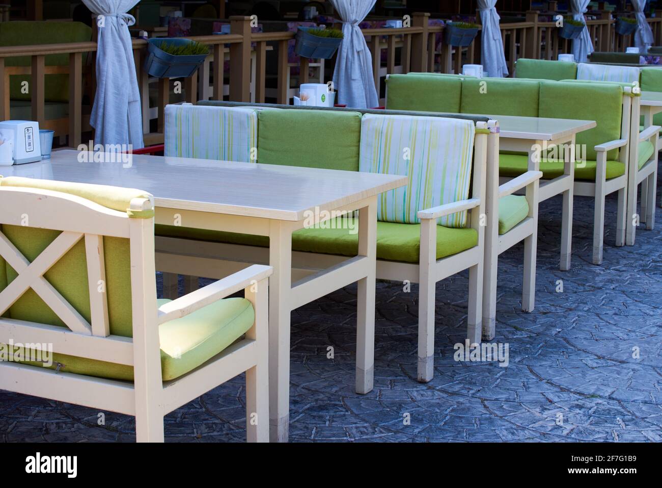 Summer terrace veranda of a cafe. Cozy green wooden chairs and tables ...