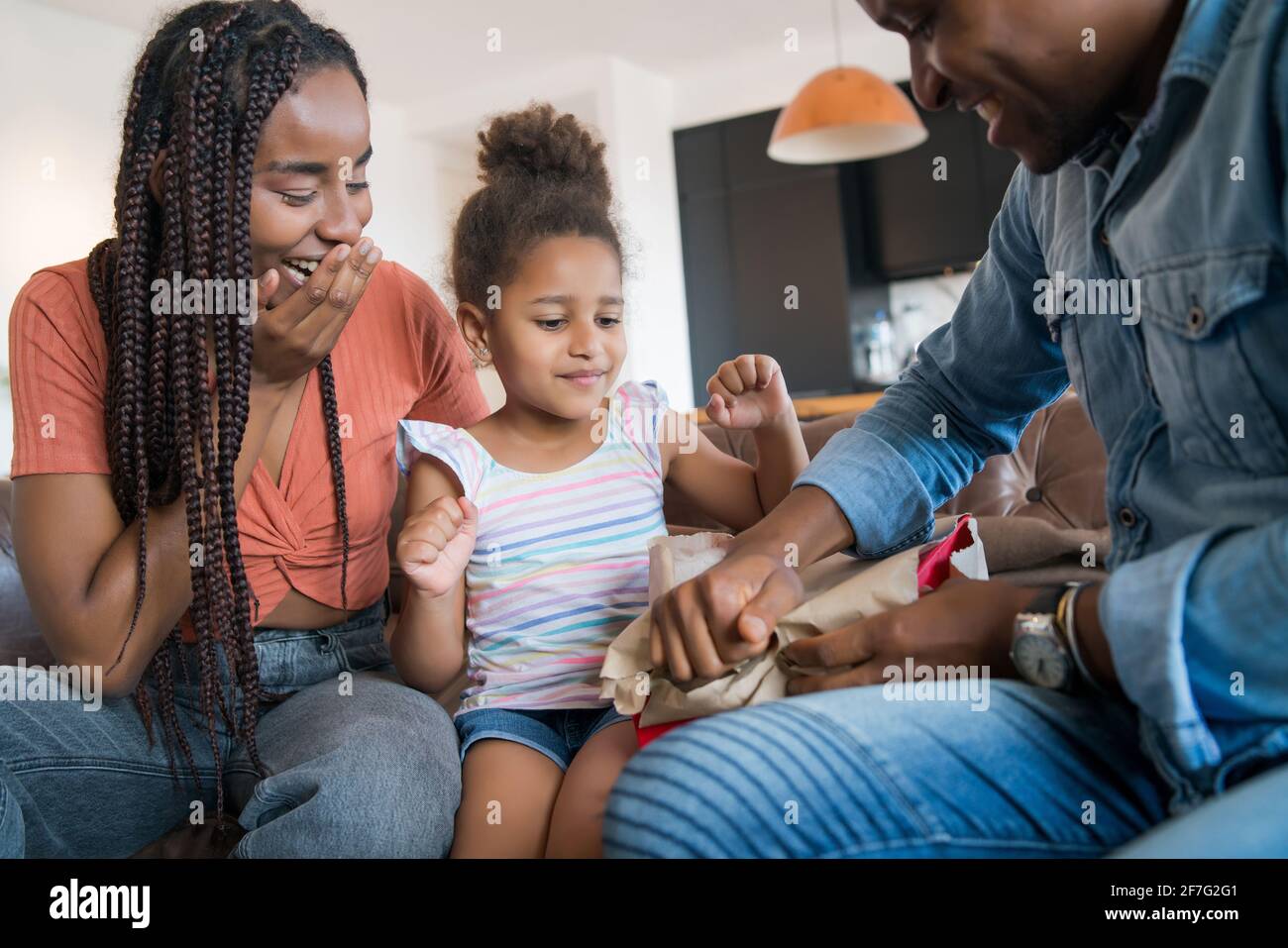 Little girl receiving gift from her parents Stock Photo - Alamy