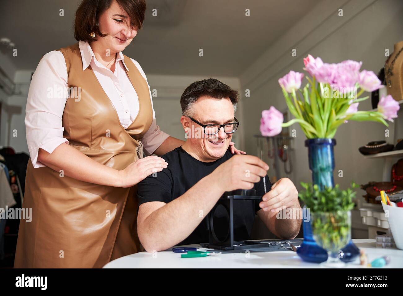 Woman watching a joyous handcrafter creating a new necklace Stock Photo ...