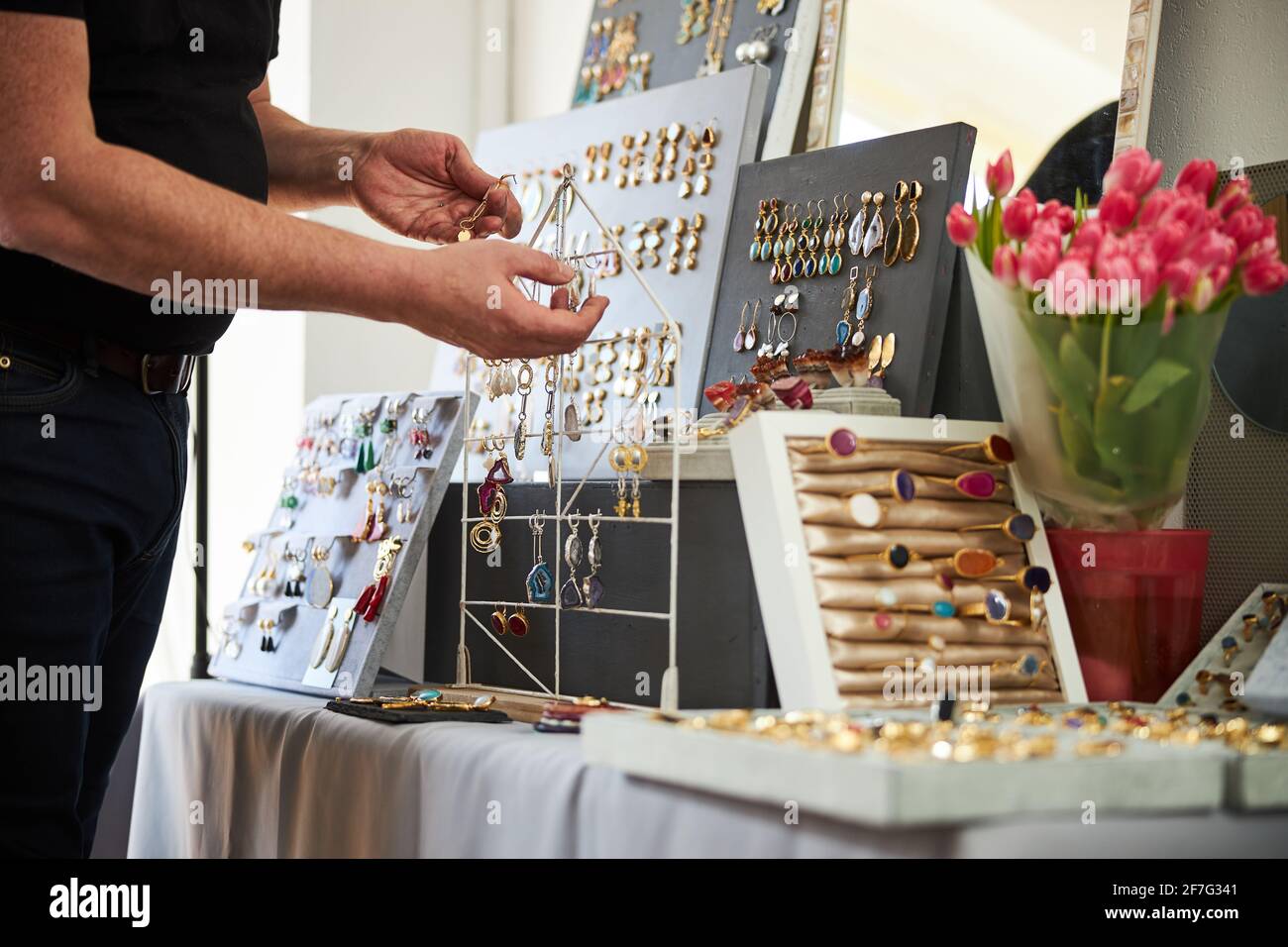 Handcrafter hanging a gold earring on the metal display rack Stock ...