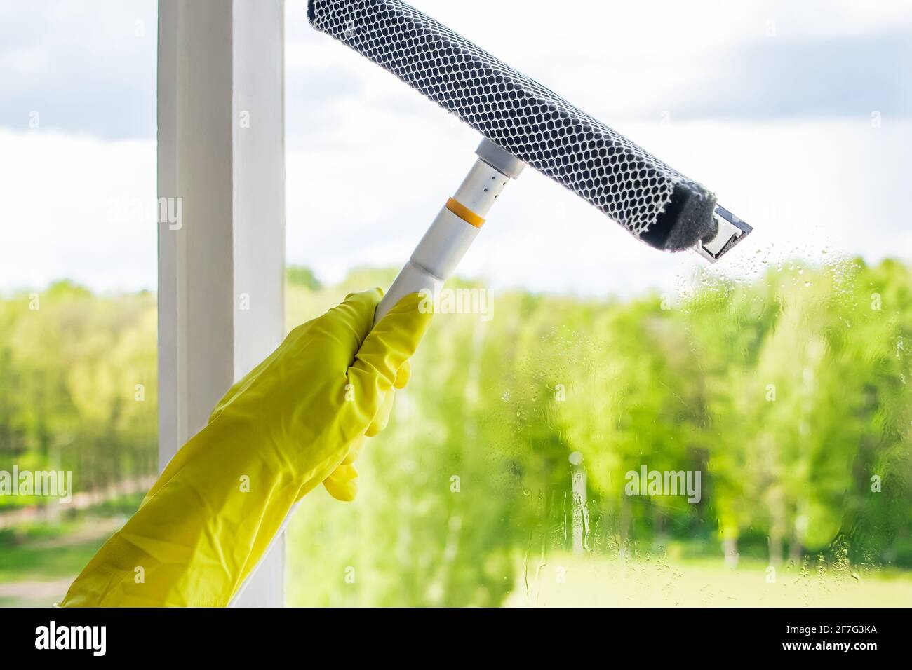 Washing windows. A young woman sprays a detergent and wipes the glass ...