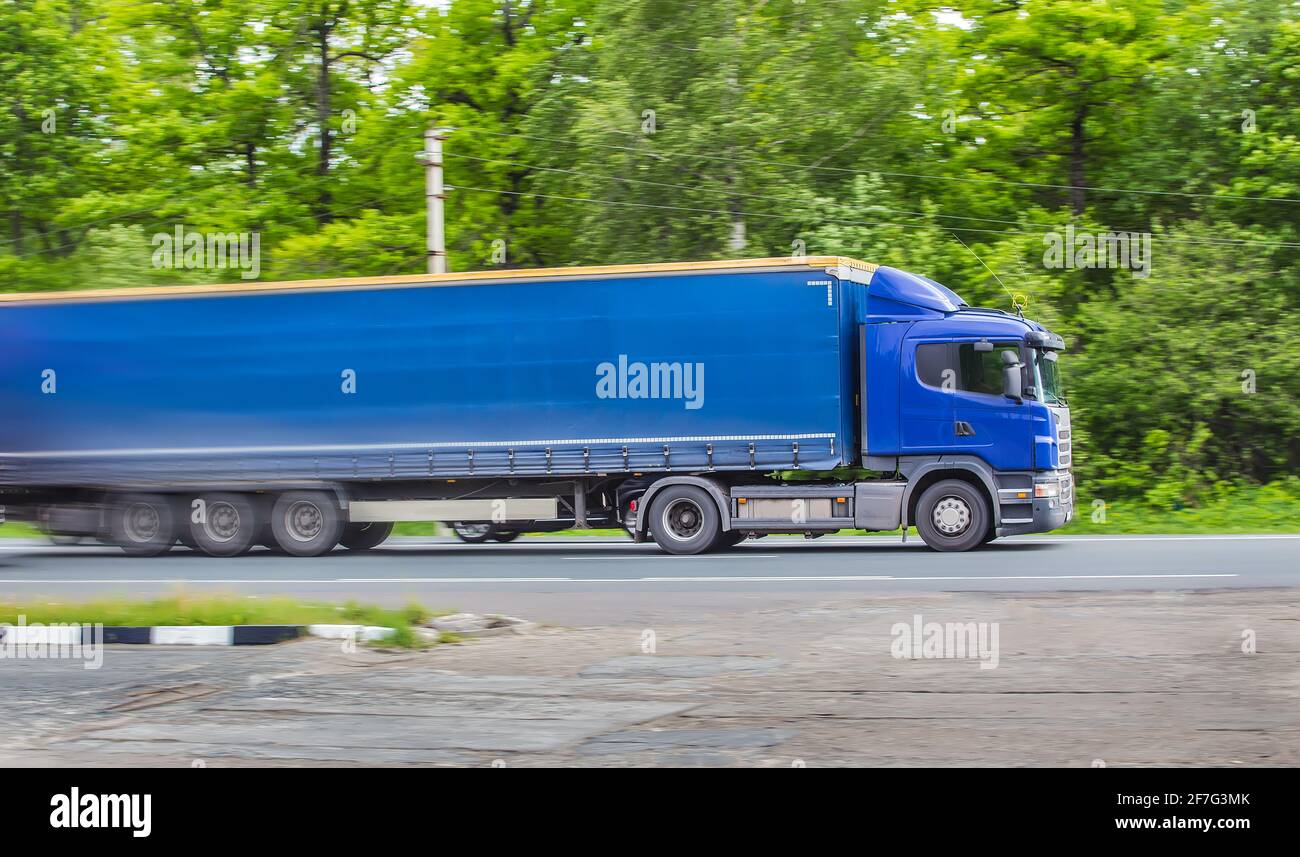 Movement of the truck is blue on the highway on the background of green ...