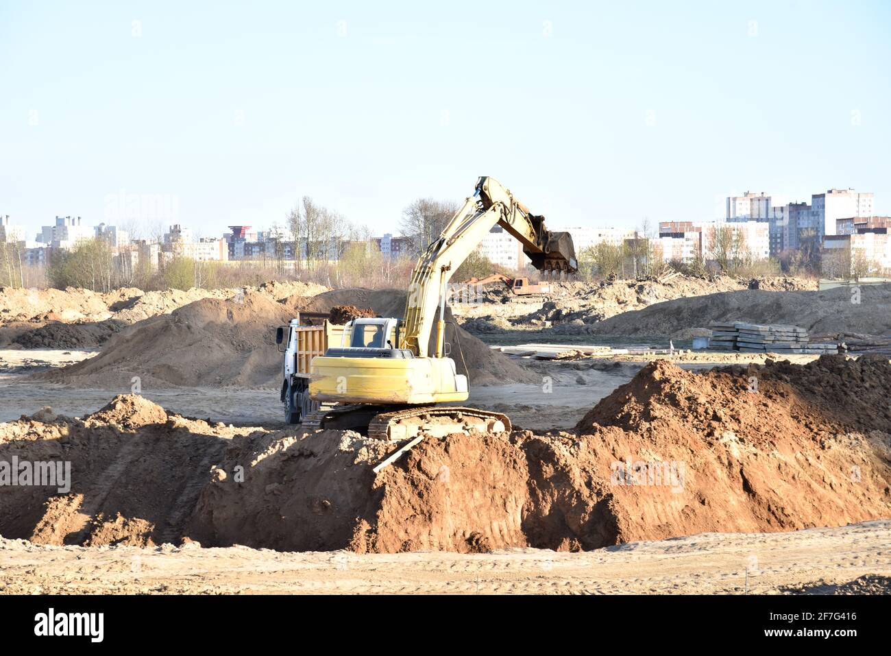 Excavator during earthmoving work at construction site. Backhoe digging ...