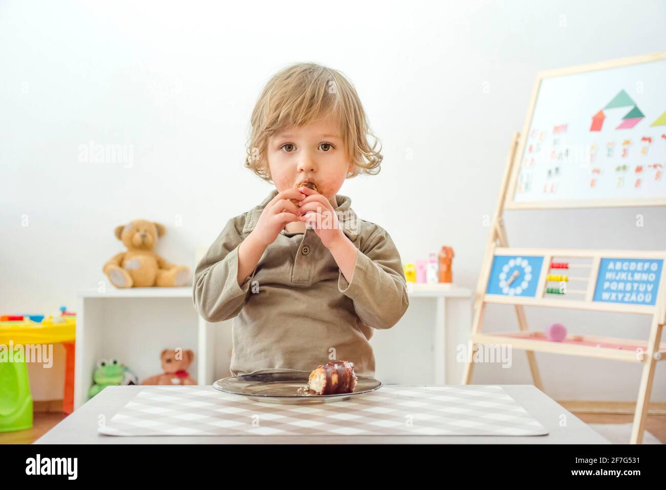 Cute happy child boy having fun eating chocolate cake at home ...