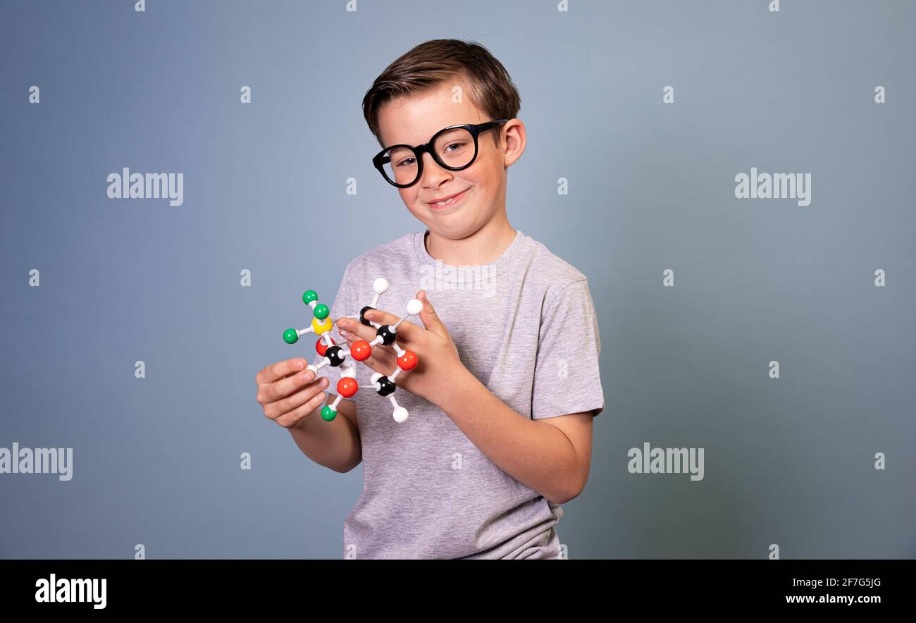 cool boy with black glasses stands in front of blue background holding ...