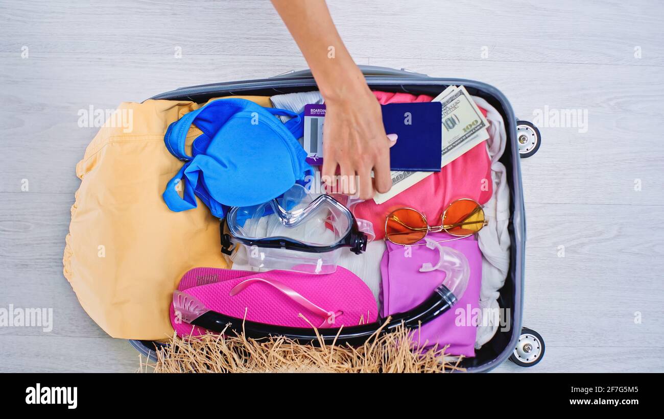 partial view of woman putting passport while packing suitcase with ...