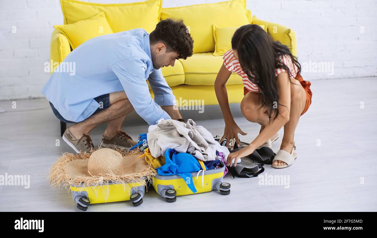 man and woman packing yellow suitcase in living room Stock Photo - Alamy