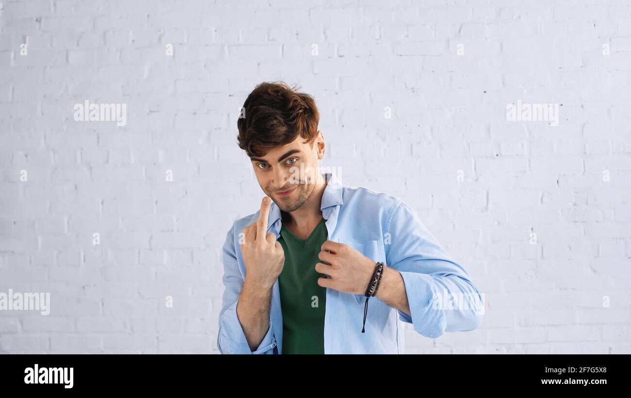 smiling man showing middle finger and looking at camera Stock Photo - Alamy