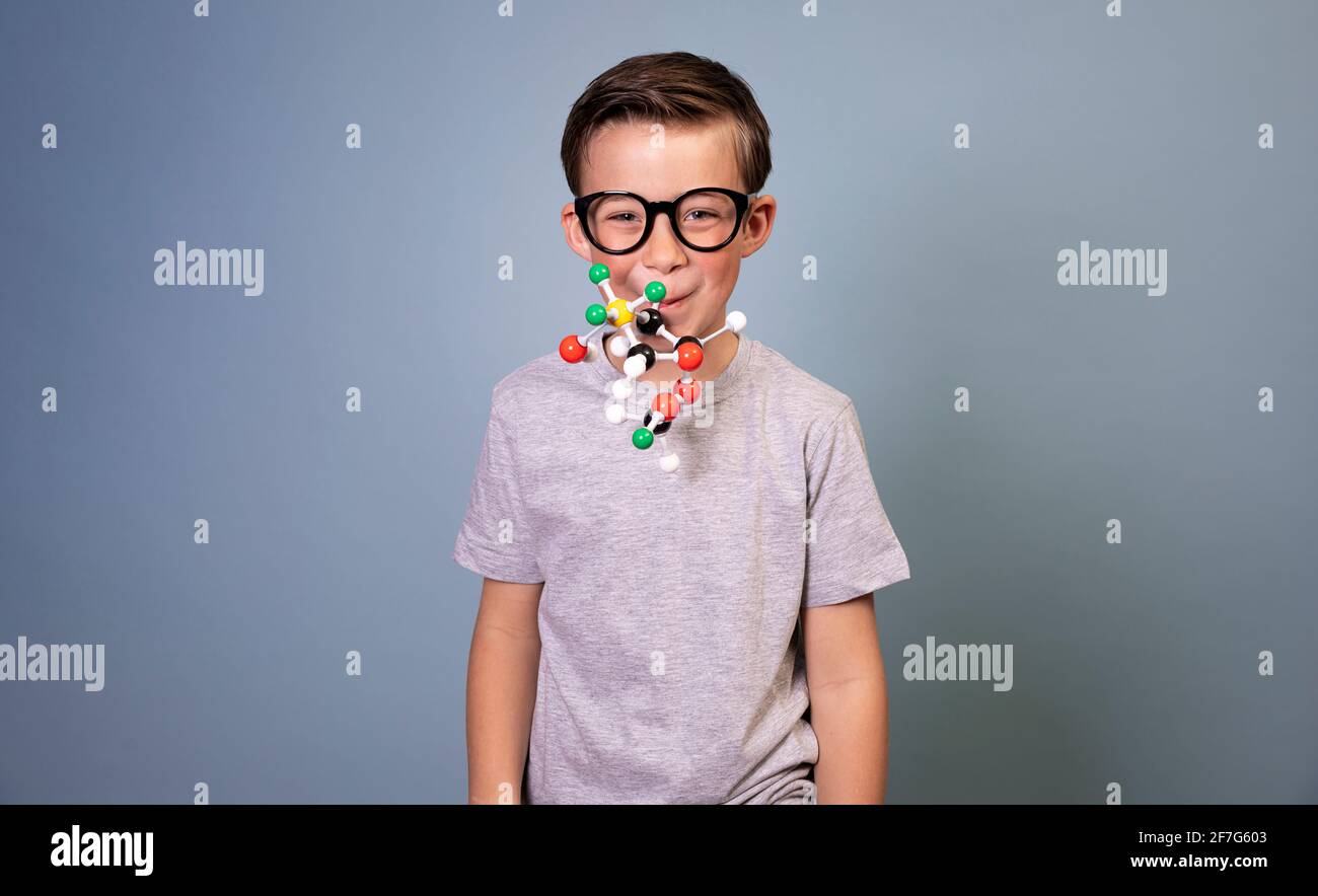 cool boy with black glasses stands in front of blue background holding ...