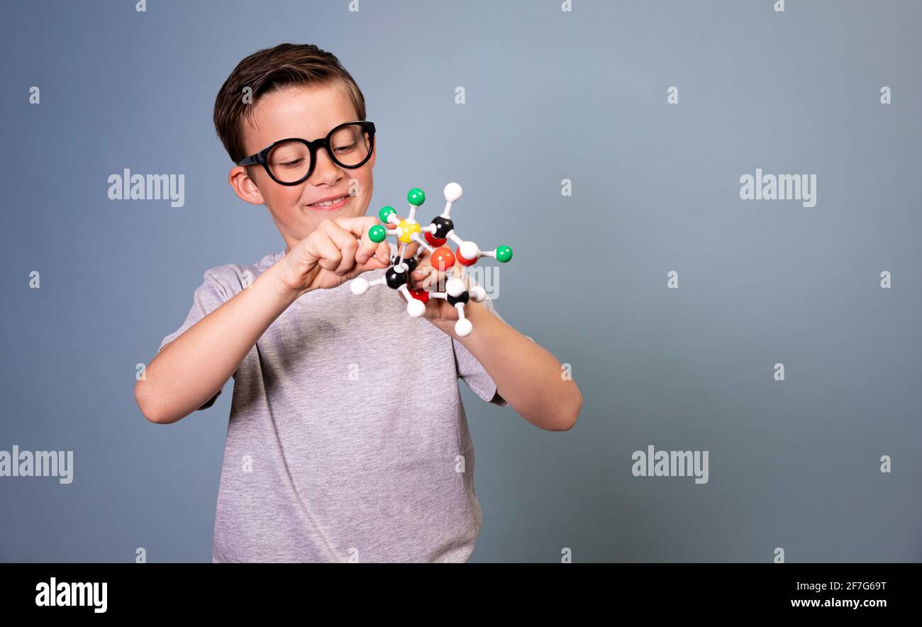 cool boy with black glasses stands in front of blue background holding ...