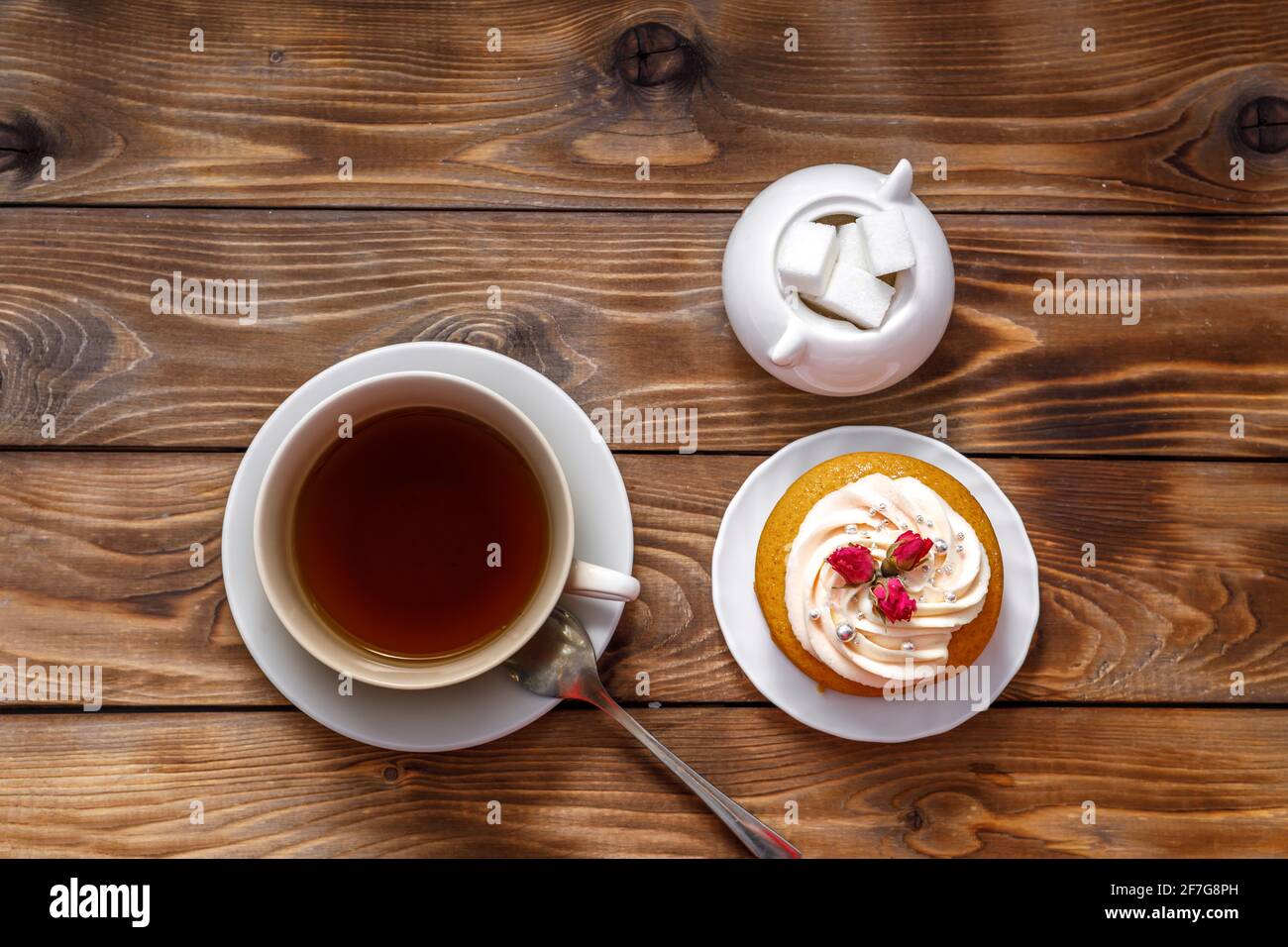 Sponge cake with cream, decorated with small flowers and a cup of tea ...