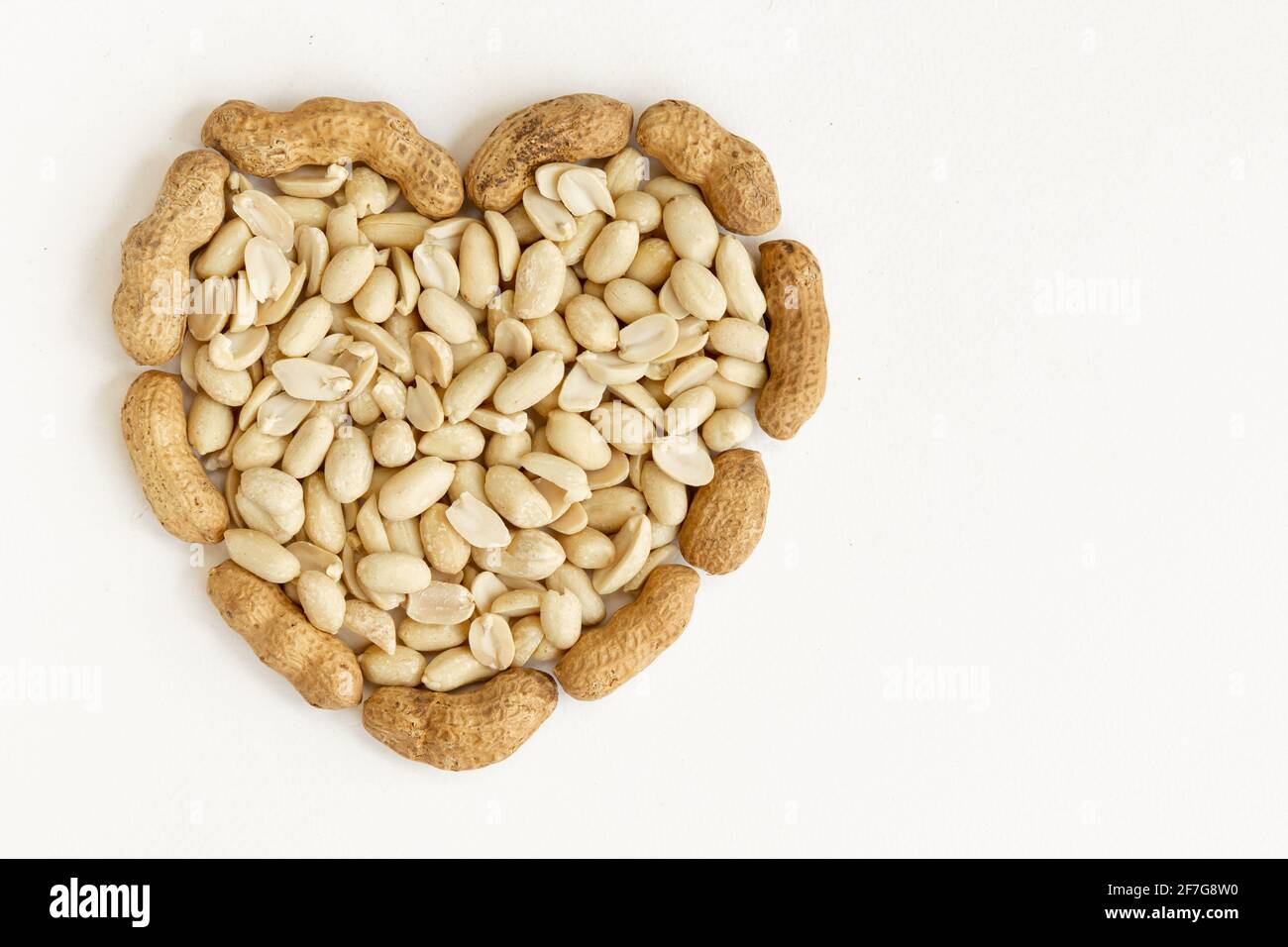 Salted peeled peanuts in a heart shape isolated on white background ...