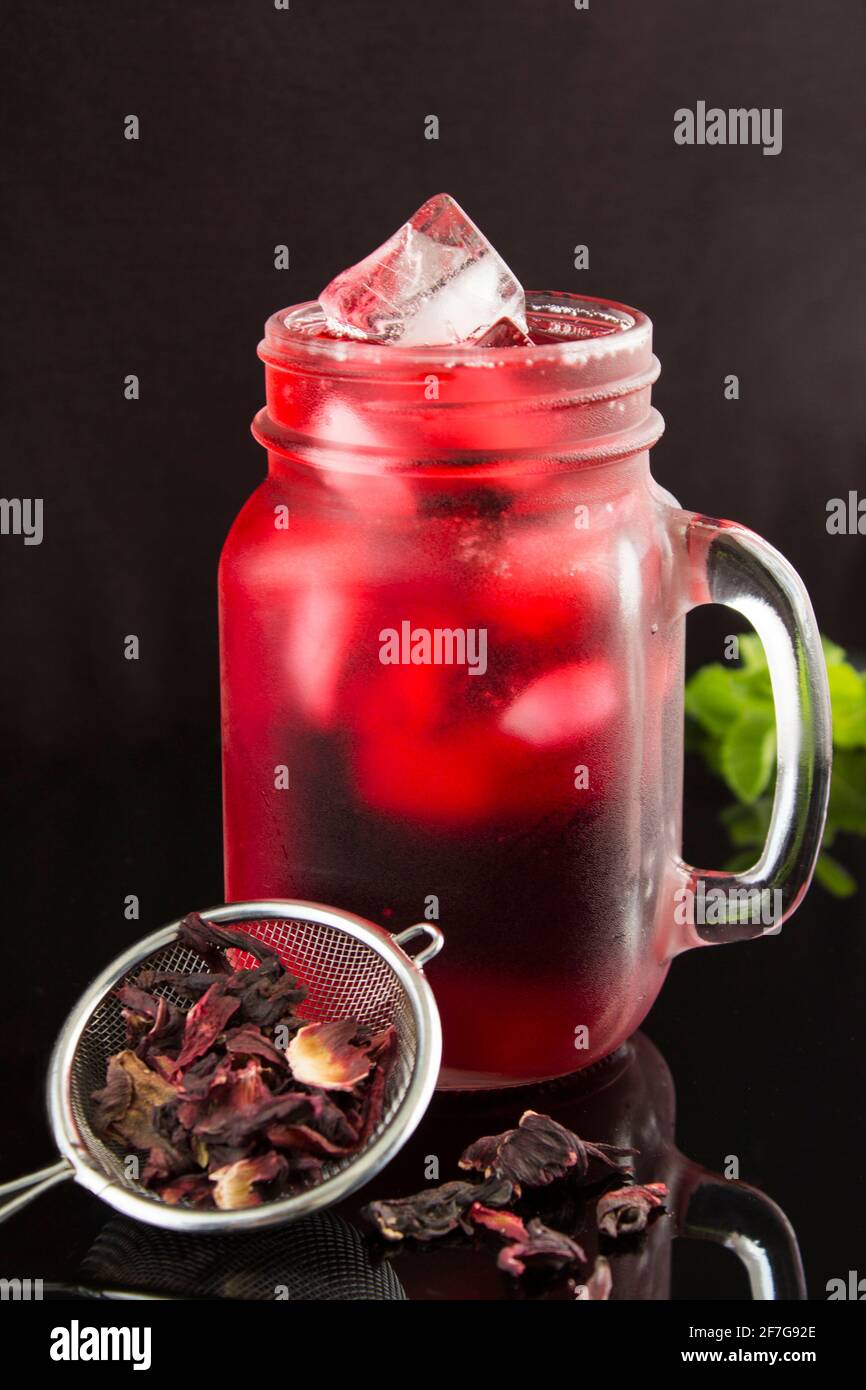 Iced hibiscus or karkade tea in the glass on the black background ...